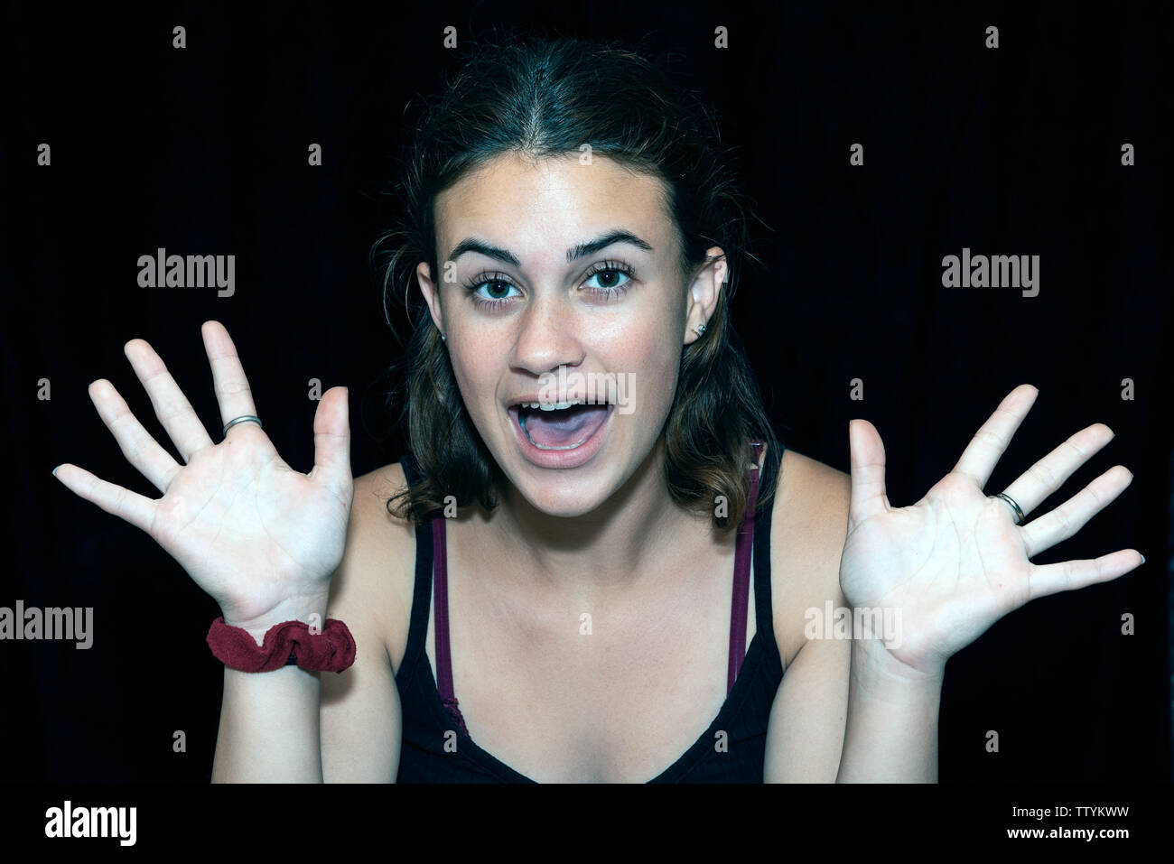 Surprised teenager girl reacting with hands up during night time Stock ...