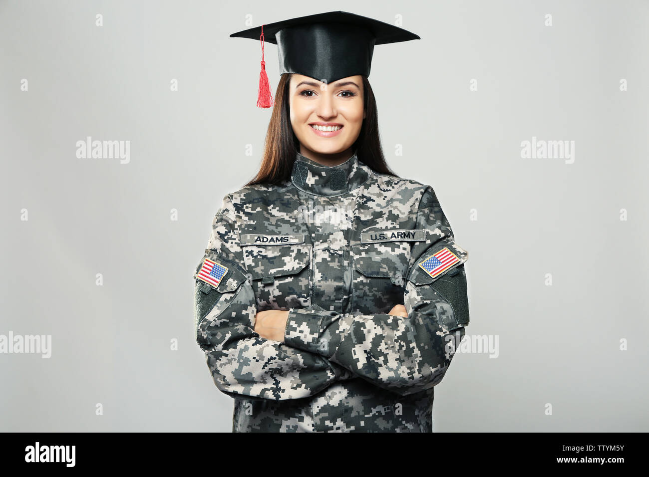 Pretty female soldier wearing graduation cap, on grey background Stock ...