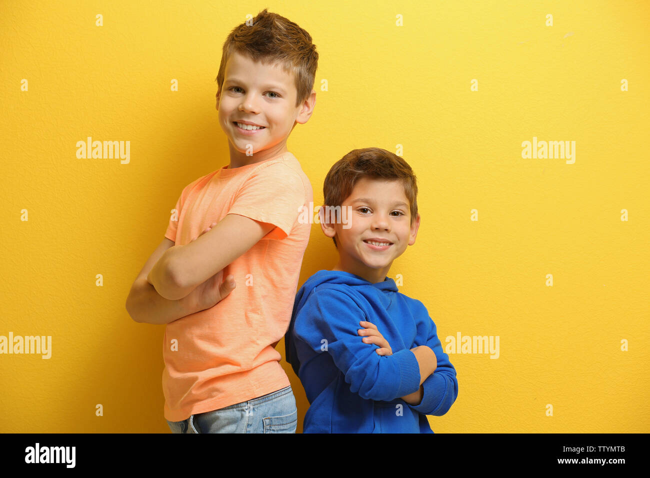 Cute little brothers standing on yellow background Stock Photo - Alamy