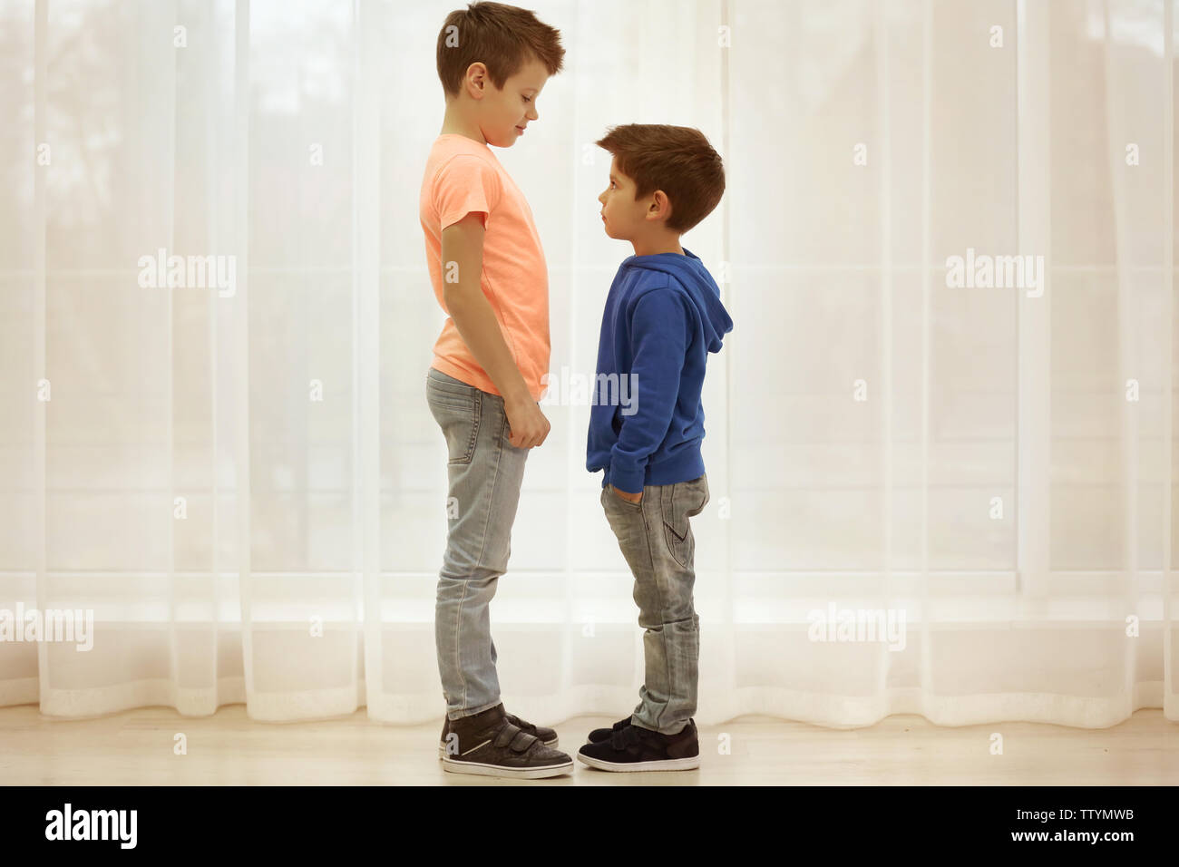 Little brothers standing together near window at home Stock Photo - Alamy