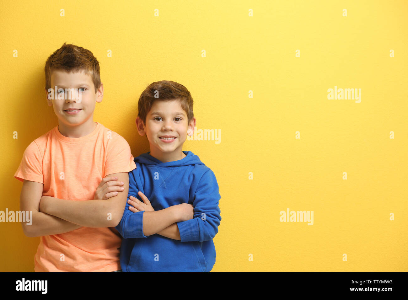 Cute little brothers standing on yellow background Stock Photo - Alamy
