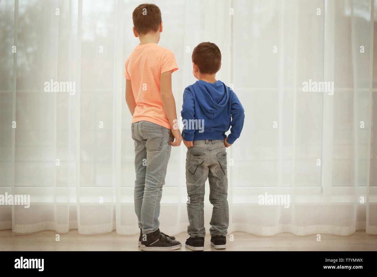 Little brothers standing together near window at home Stock Photo - Alamy