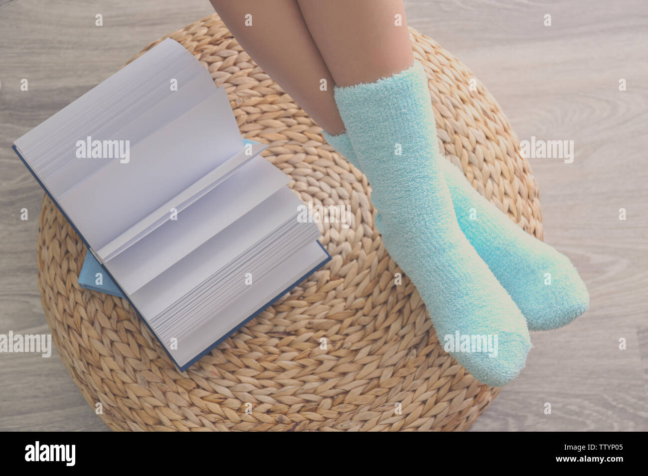Human legs in knitted socks on ottoman beside open book Stock Photo - Alamy