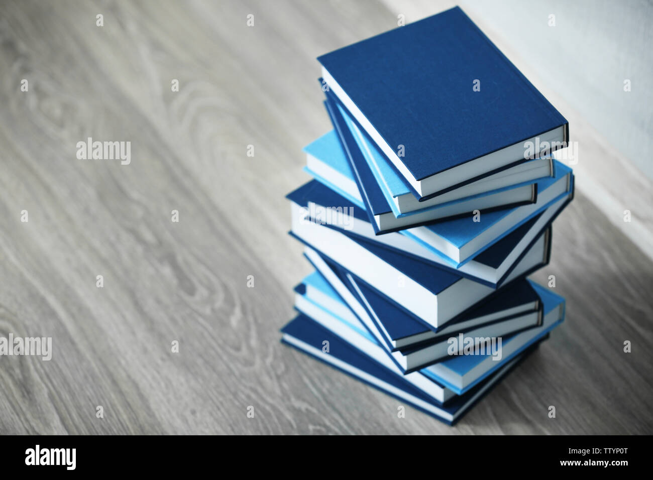 Stacked books on gray wooden floor in room Stock Photo - Alamy