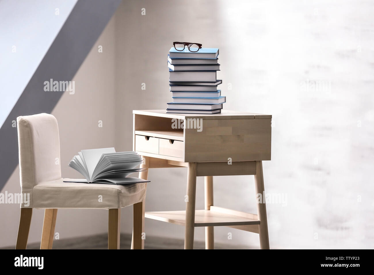 Small wooden table with books and chair in empty room Stock Photo - Alamy