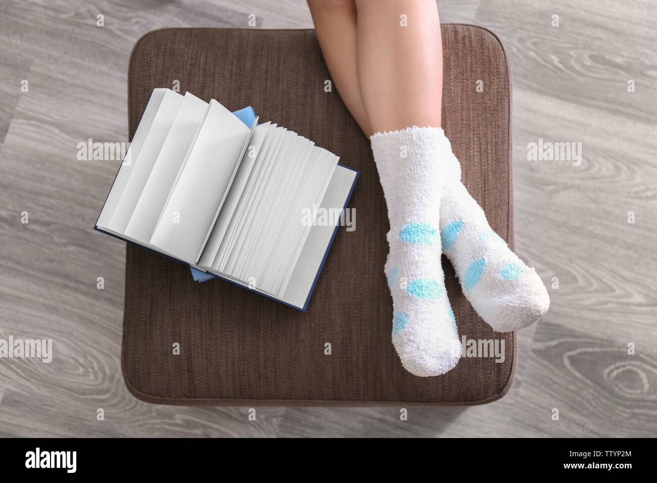 Human legs in knitted socks on ottoman beside open book Stock Photo - Alamy