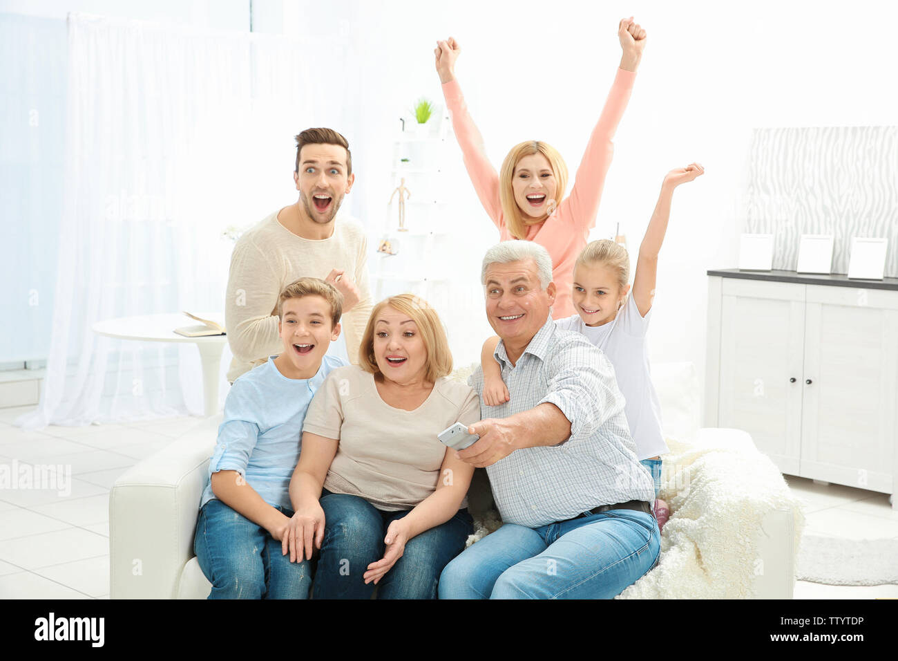 Happy family watching TV in living room Stock Photo - Alamy