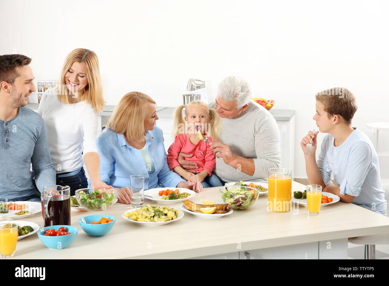 Happy family having lunch in kitchen Stock Photo - Alamy