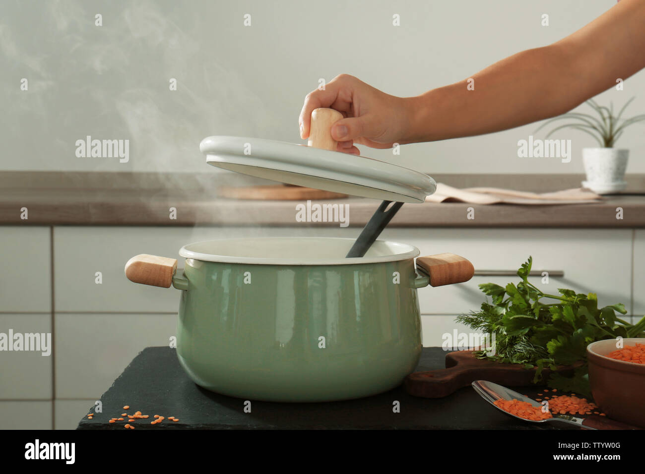 Female hand holding lid above enamelled pan in kitchen Stock Photo - Alamy