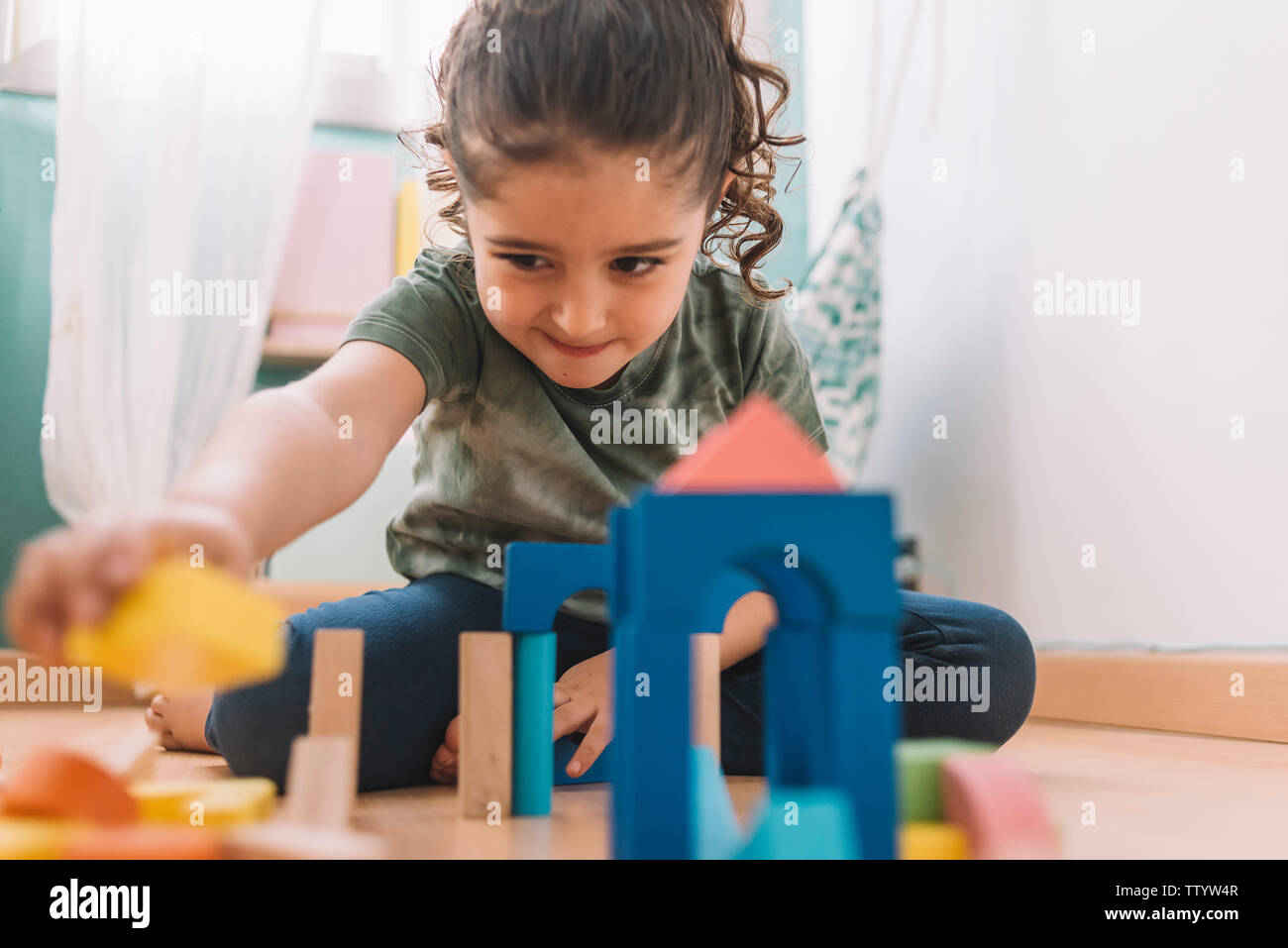 child little girl playing constructions on the floor with wooden ...