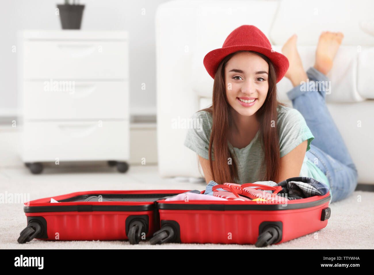 Beautiful young woman packing suitcase at home Stock Photo - Alamy