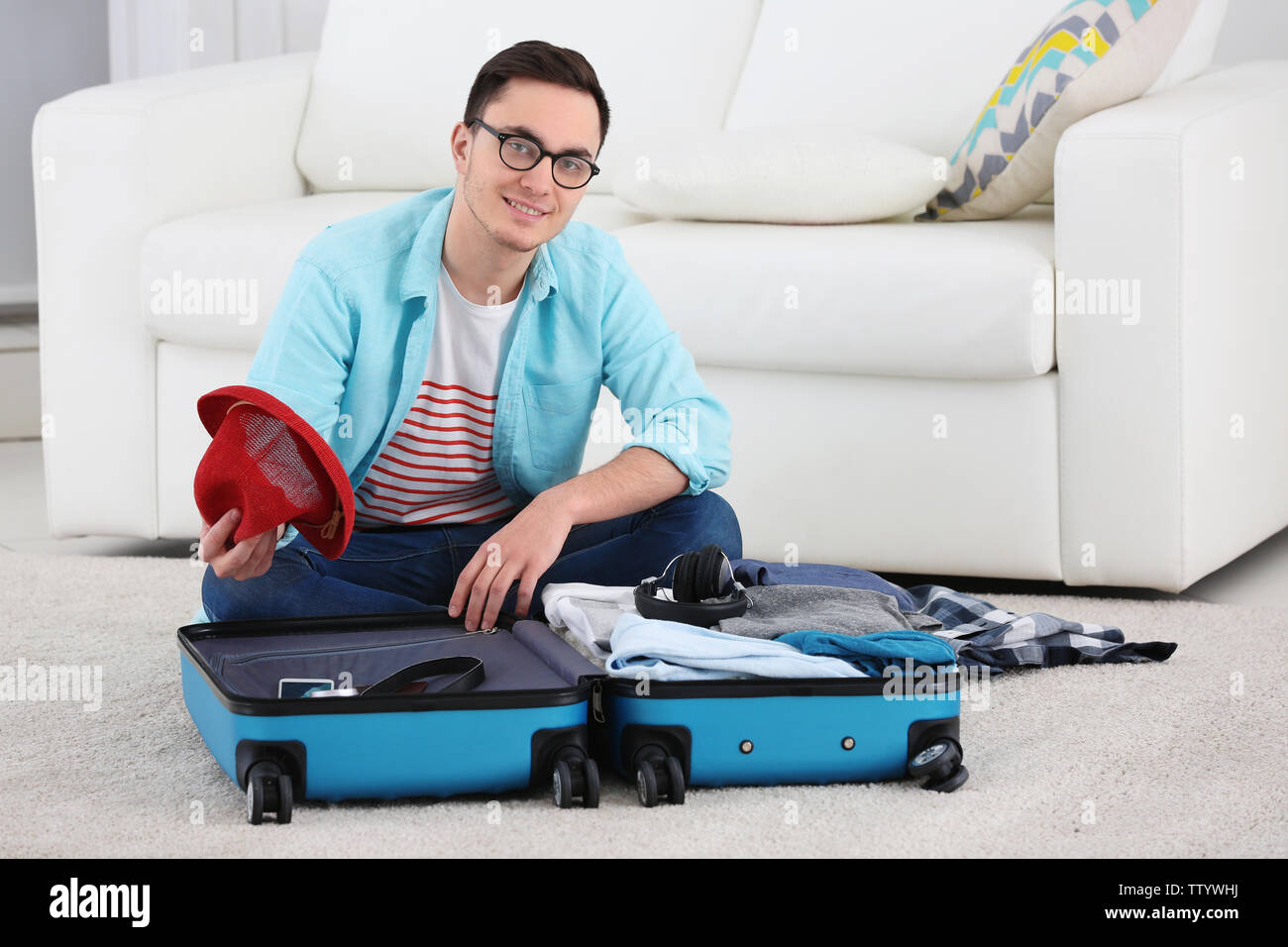 Handsome young man packing suitcase at home Stock Photo - Alamy