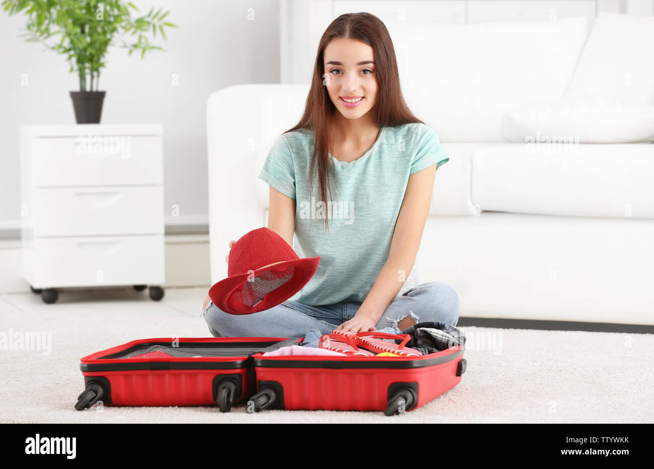 Beautiful young woman packing suitcase at home Stock Photo - Alamy