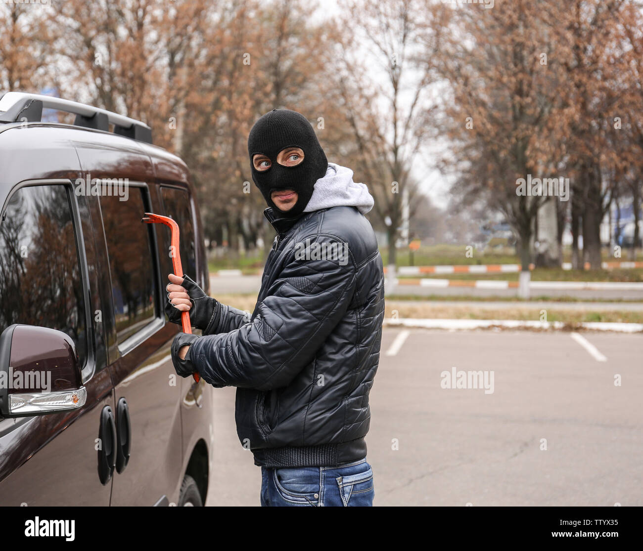 Male thief going to break car window with crowbar Stock Photo - Alamy