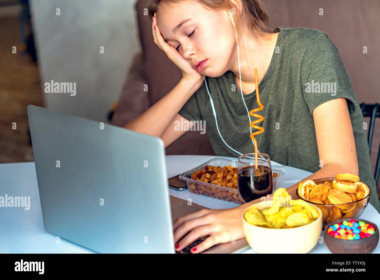 Girl works at a computer and eats fast food. Unhealthy food: chips ...