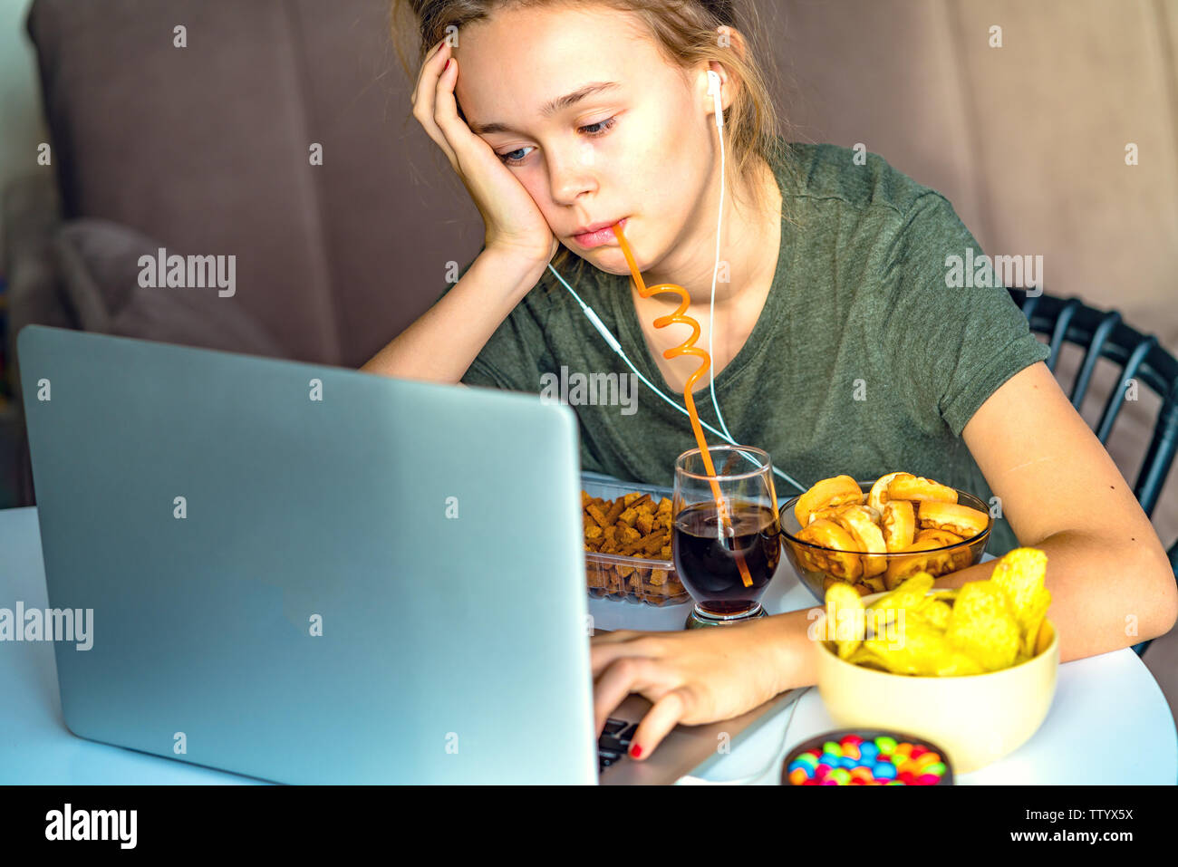 Girl works at a computer and eats fast food. Unhealthy food: chips ...