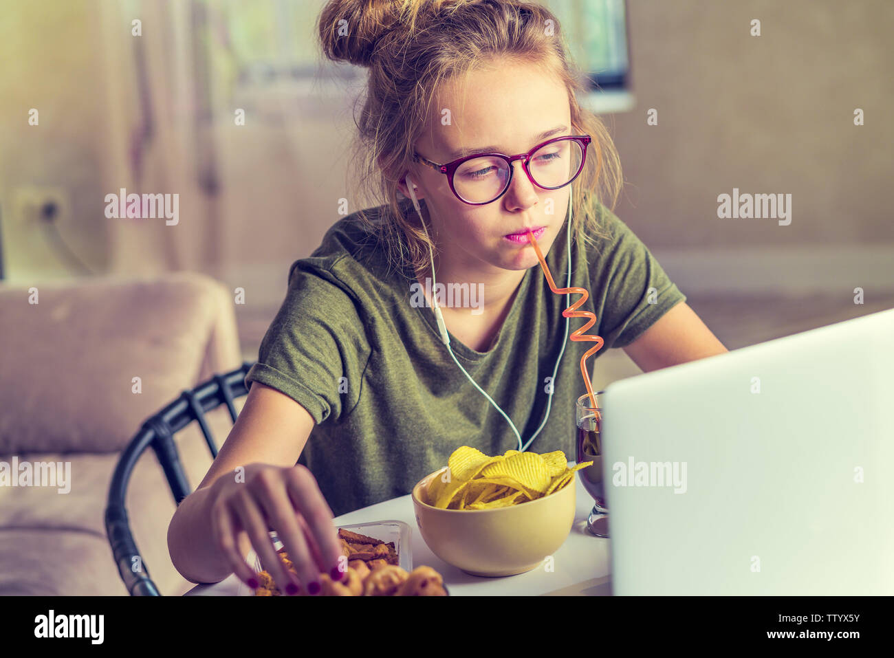 Girl works at a computer and eats fast food. Unhealthy food: chips ...