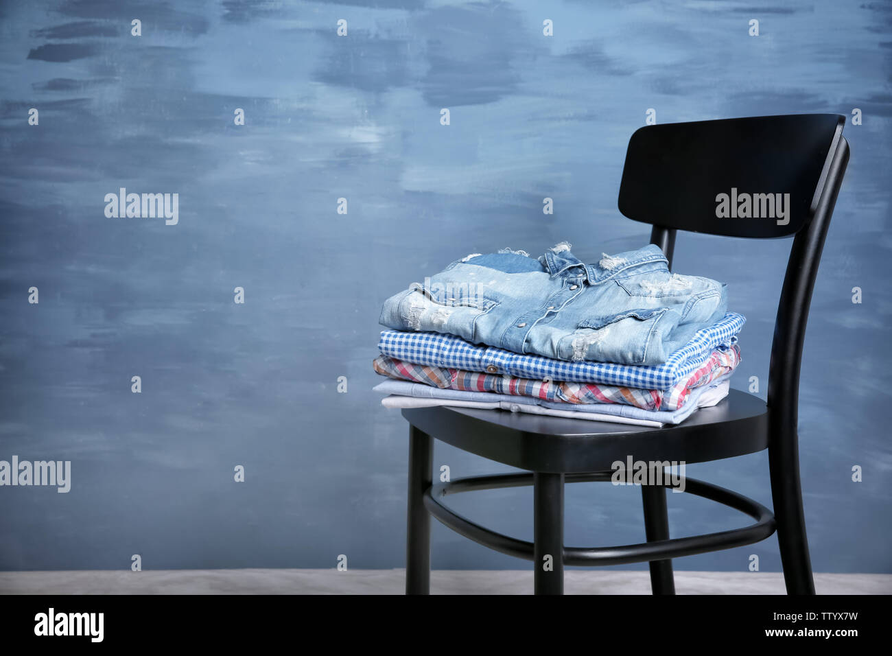 Pile of clothes on wooden chair Stock Photo - Alamy