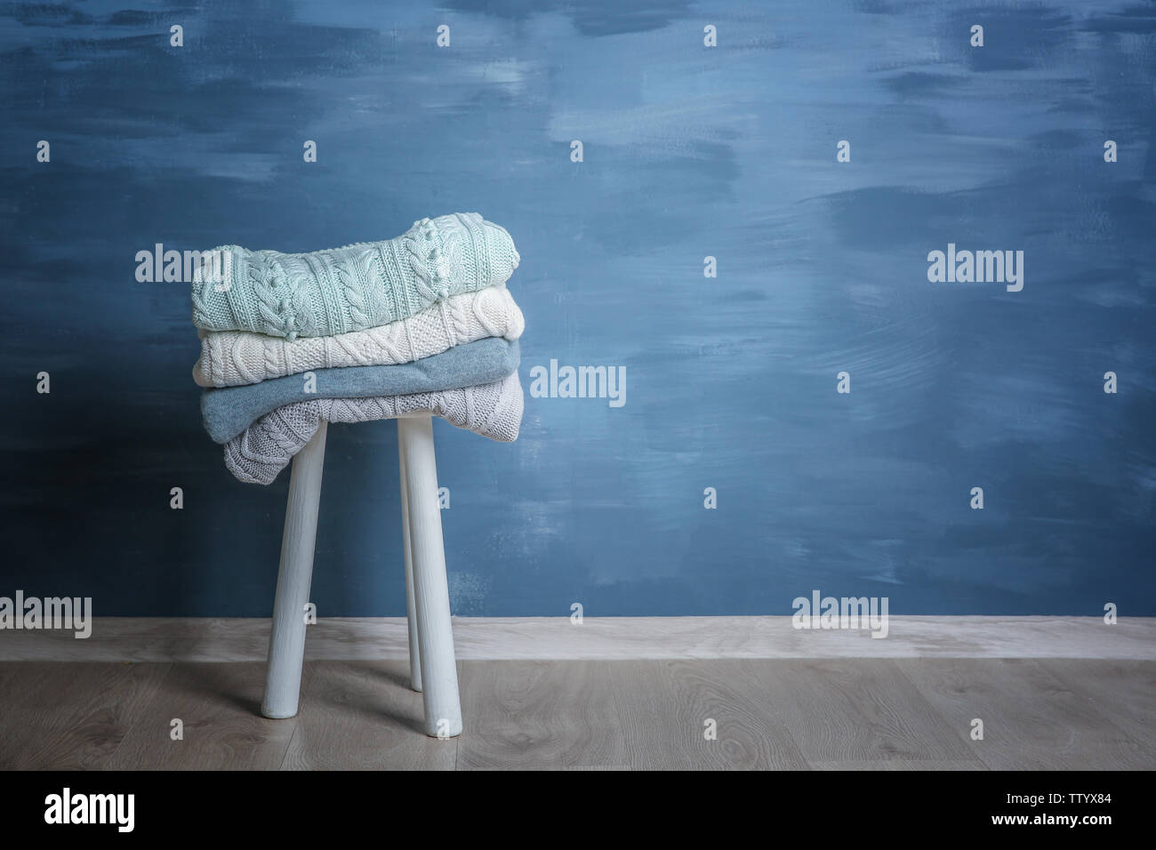 Pile of clothes on wooden stool Stock Photo - Alamy