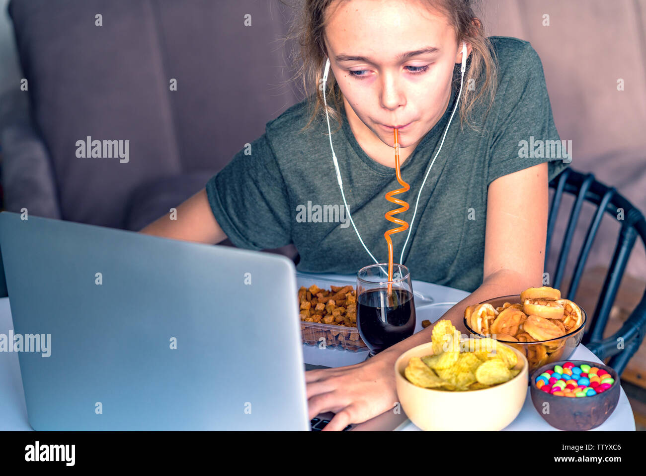 Girl works at a computer and eats fast food. Unhealthy food: chips ...