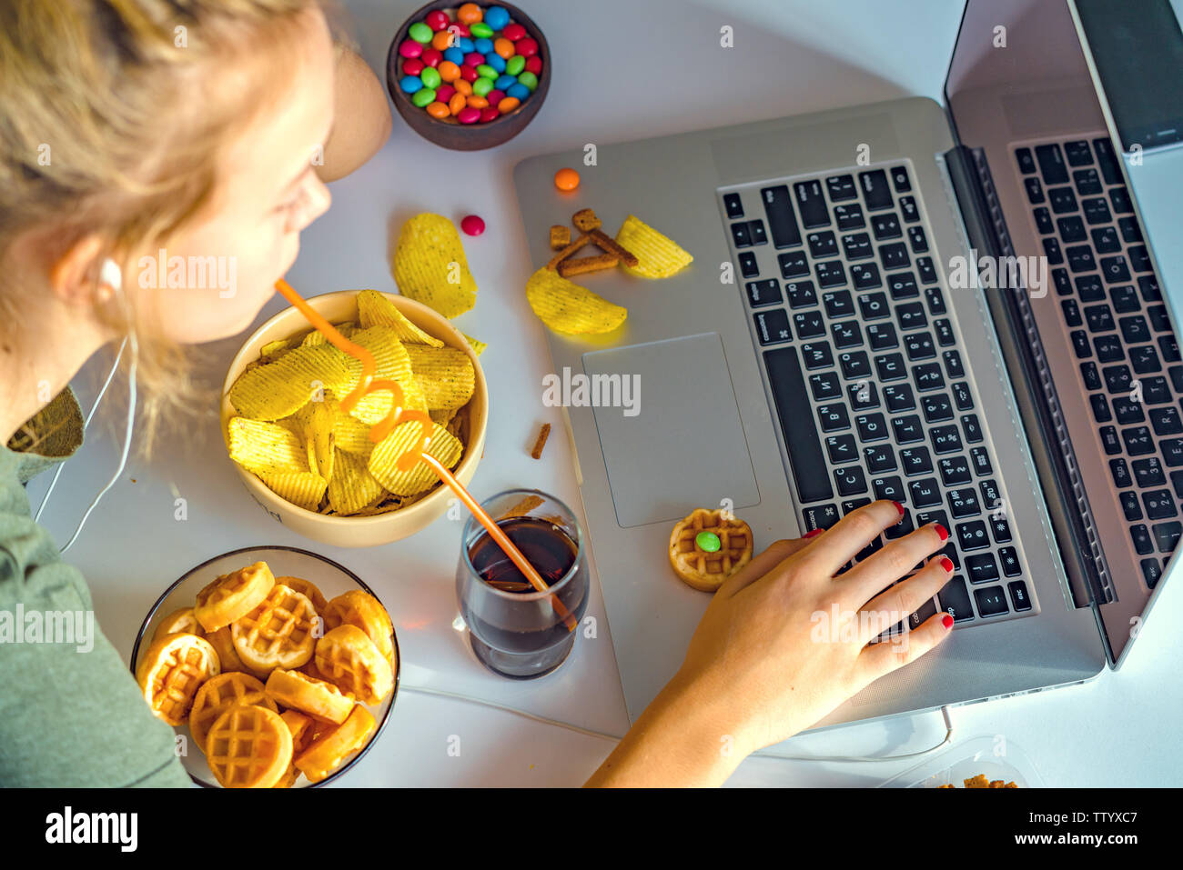 Girl works at a computer and eats fast food. Unhealthy food: chips ...