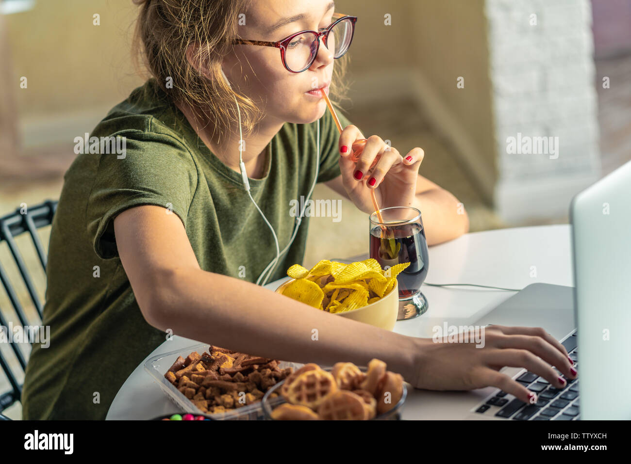 Girl works at a computer and eats fast food. Unhealthy food: chips ...