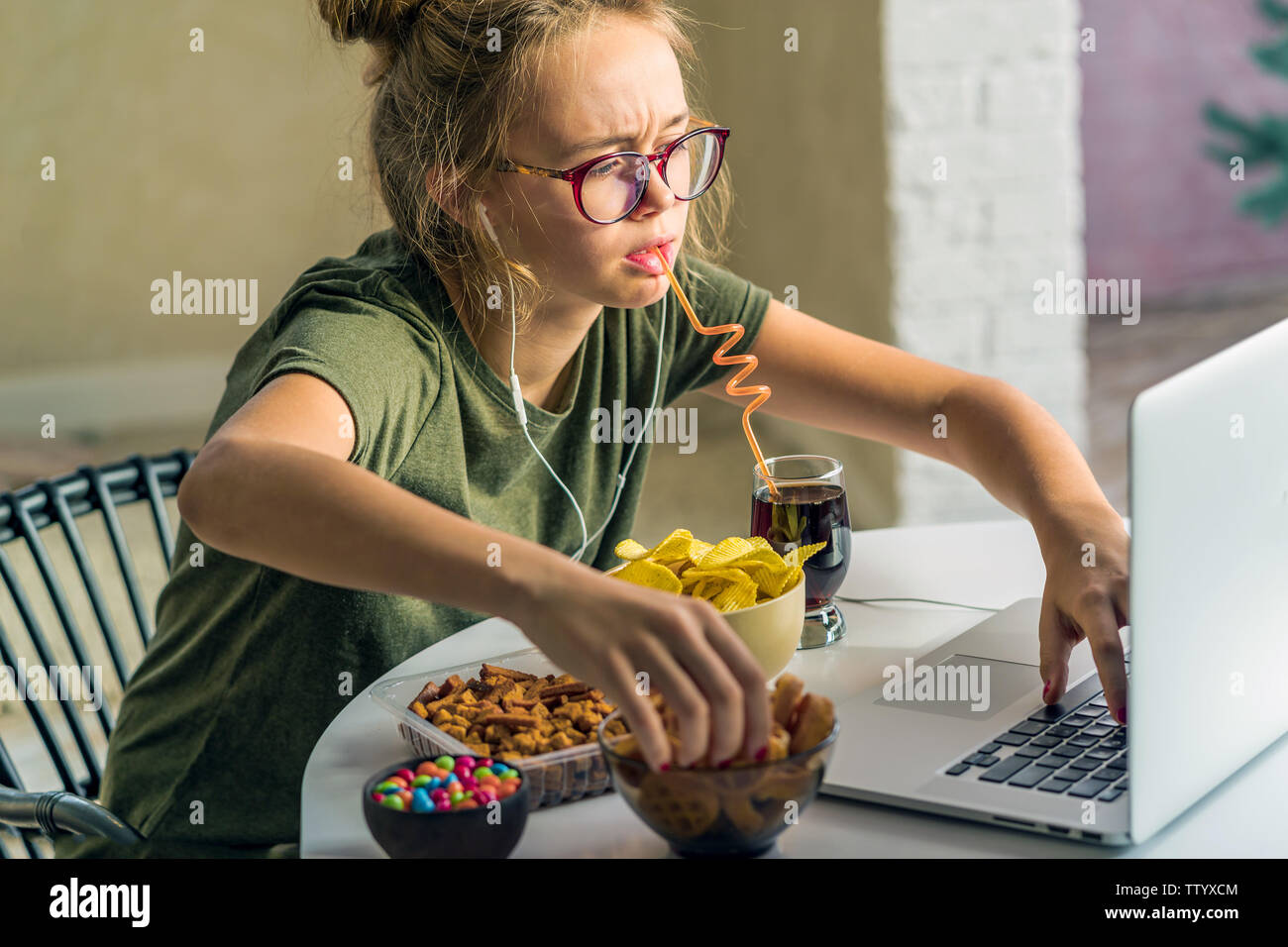 Girl works at a computer and eats fast food. Unhealthy food: chips ...