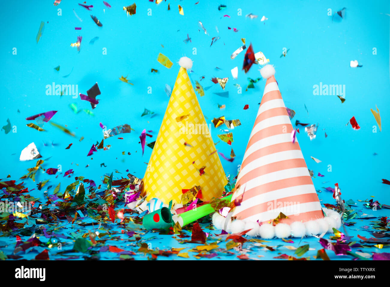 Party hats with colorful confetti on color background Stock Photo - Alamy