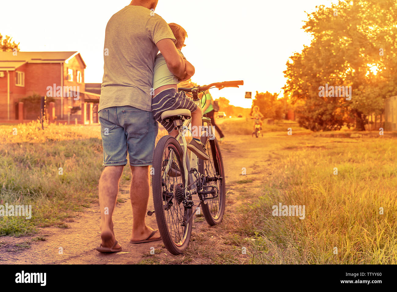 Father is teaching sun how to ride bicycle near their private house ...