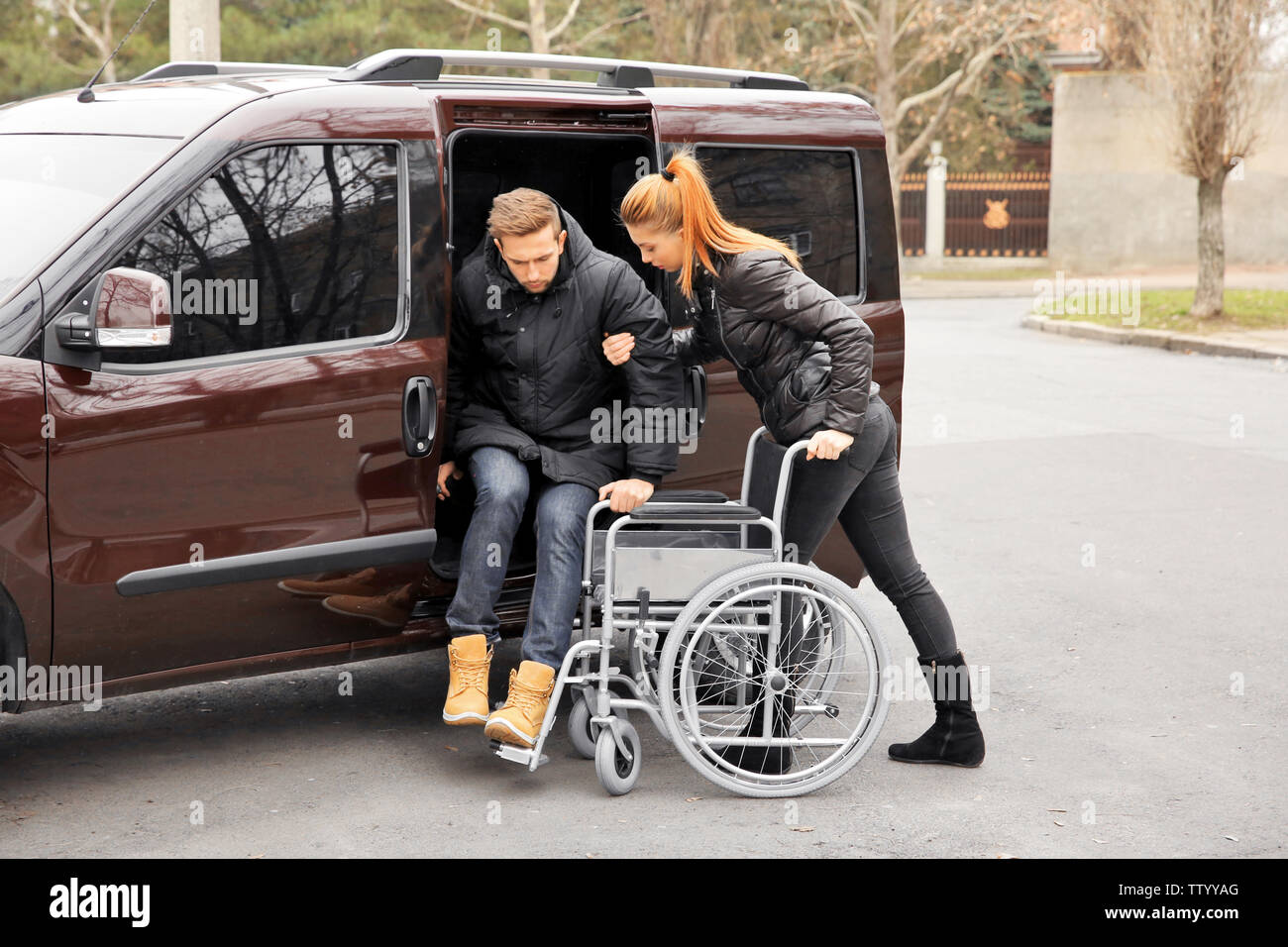 Young woman helping handicapped man to sit in wheelchair Stock Photo ...