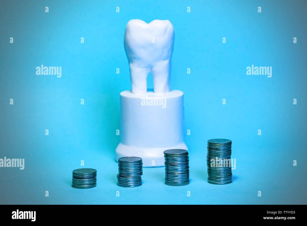 Closeup of a white healthy human tooth model and stacked coins ...
