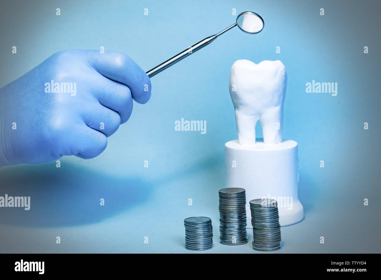 Closeup of a white healthy human tooth model and stacked coins ...