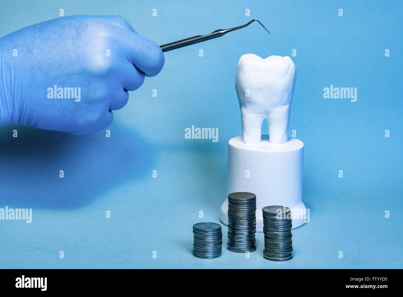 Closeup of a white healthy human tooth model and stacked coins ...