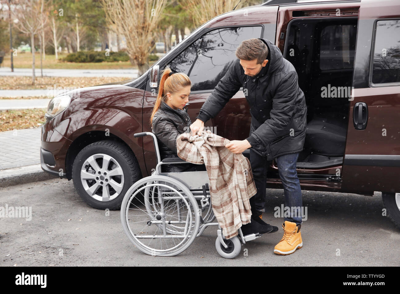 Young man helping handicapped woman to sit in wheelchair Stock Photo ...
