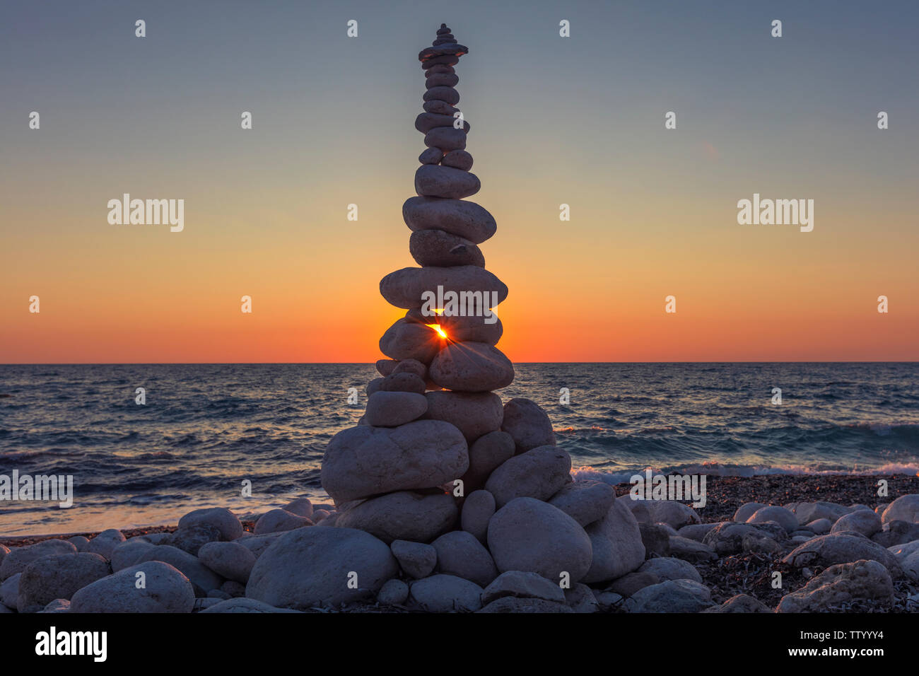 Pyramide of rounded stones by the sea at sunset Stock Photo - Alamy