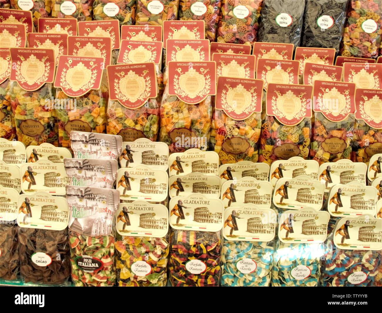 Packets of colorful italian pasta at a counter in an outdoor market ...