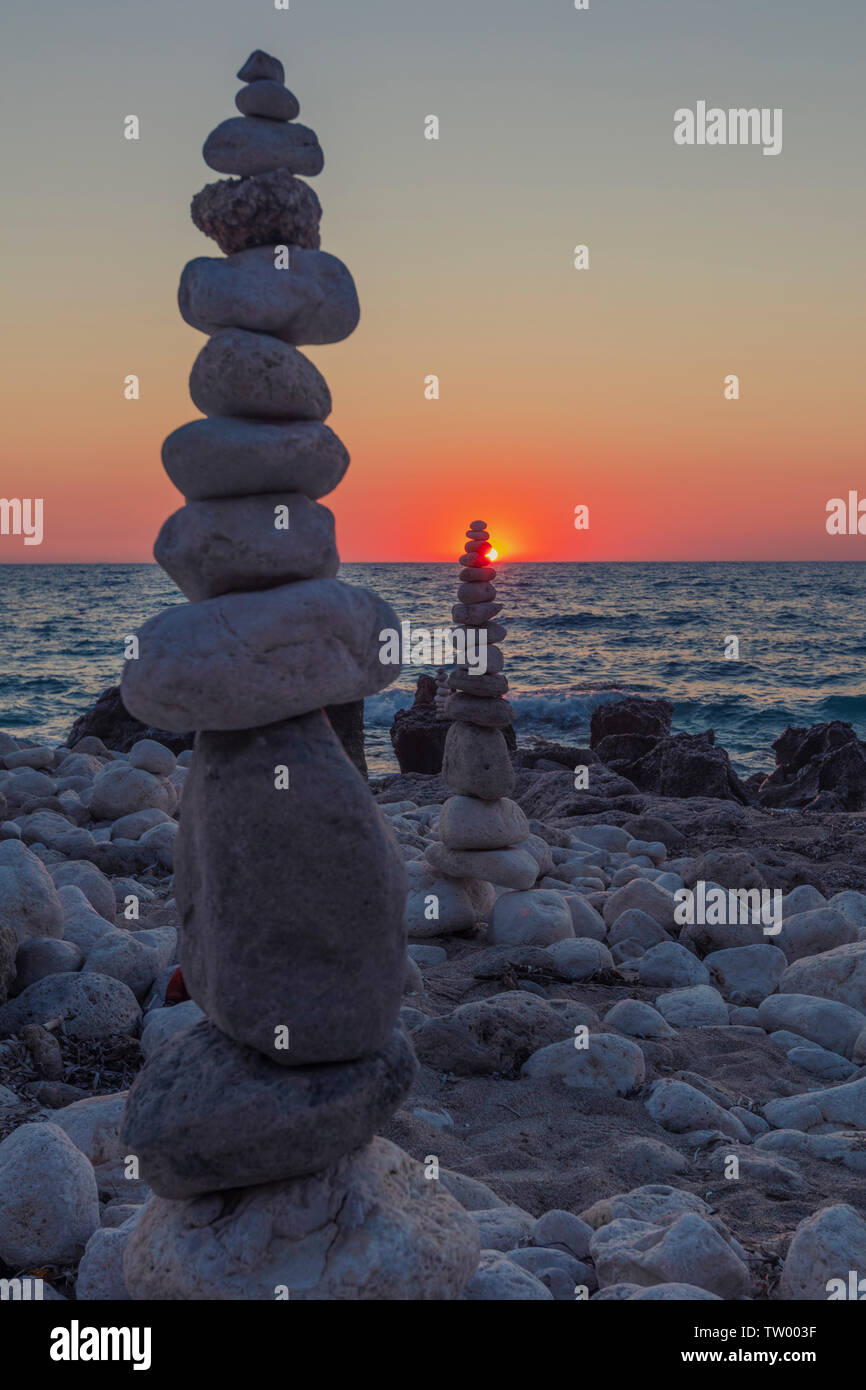 Pyramide of rounded stones by the sea at sunset Stock Photo - Alamy