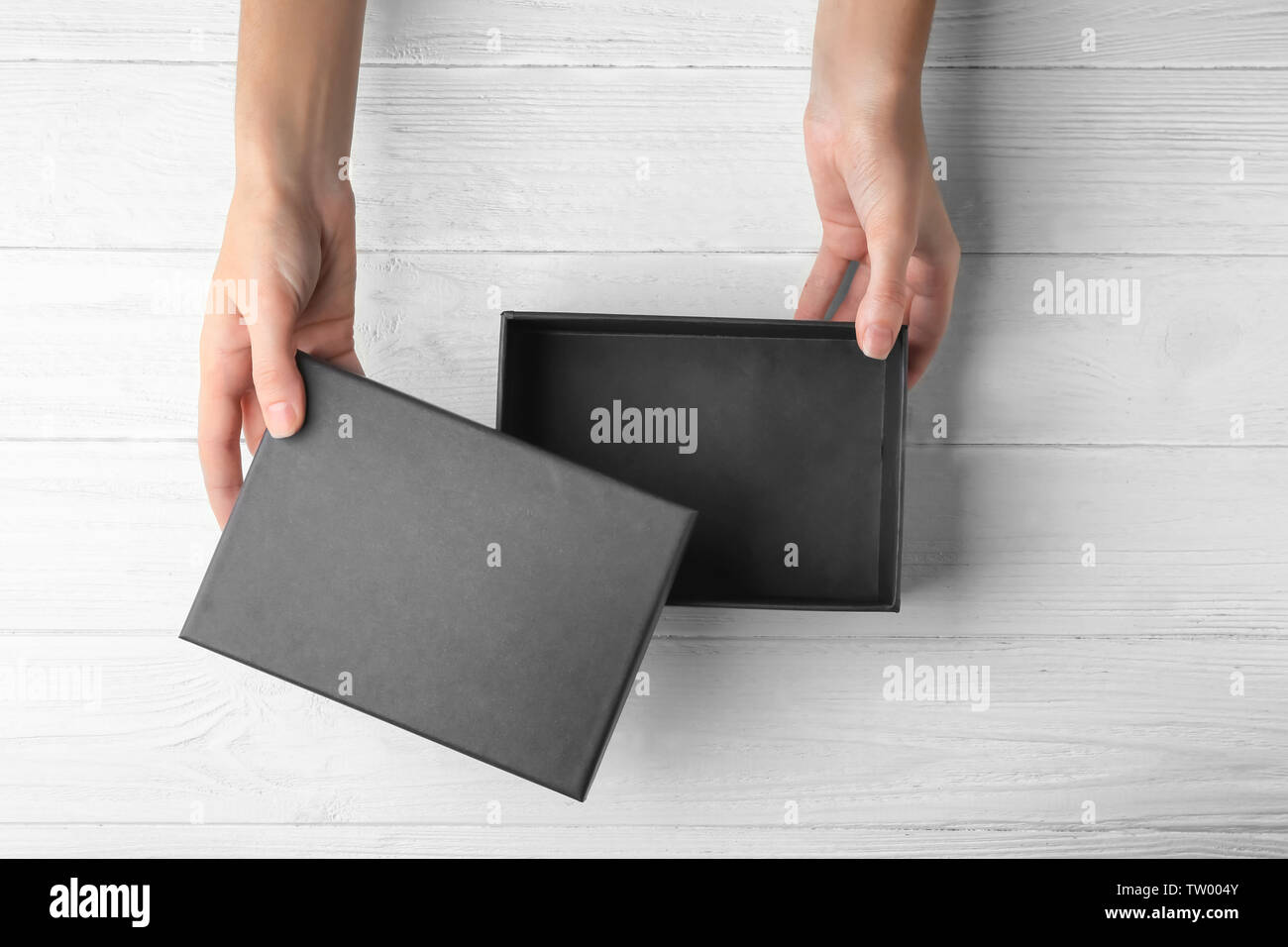 Female hands opening black box, on wooden background Stock Photo - Alamy