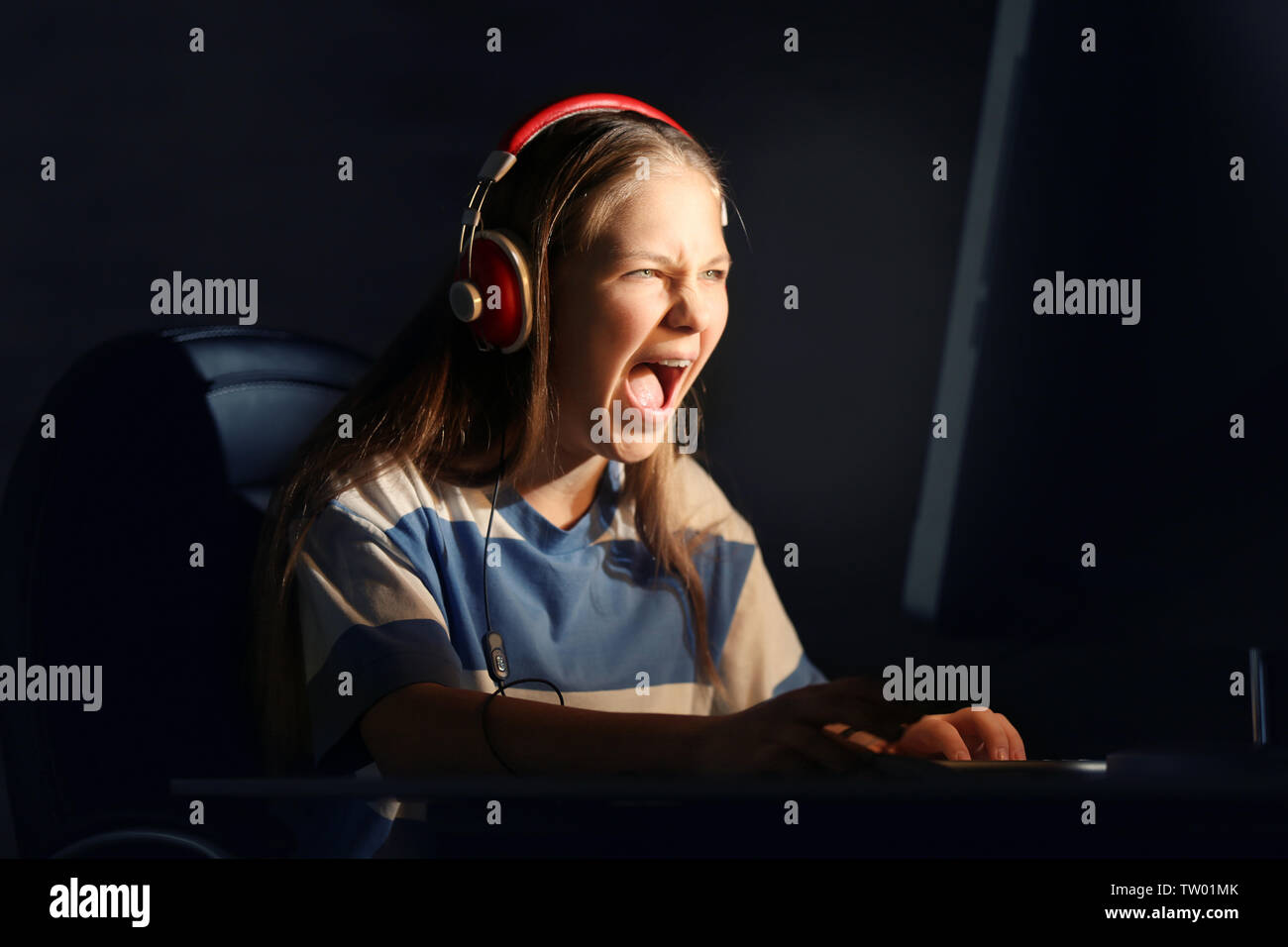 Pretty teenager playing computer game at home late in evening Stock ...