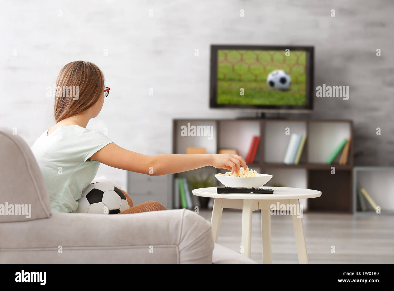 Pretty teenager watching football match on TV at home Stock Photo - Alamy
