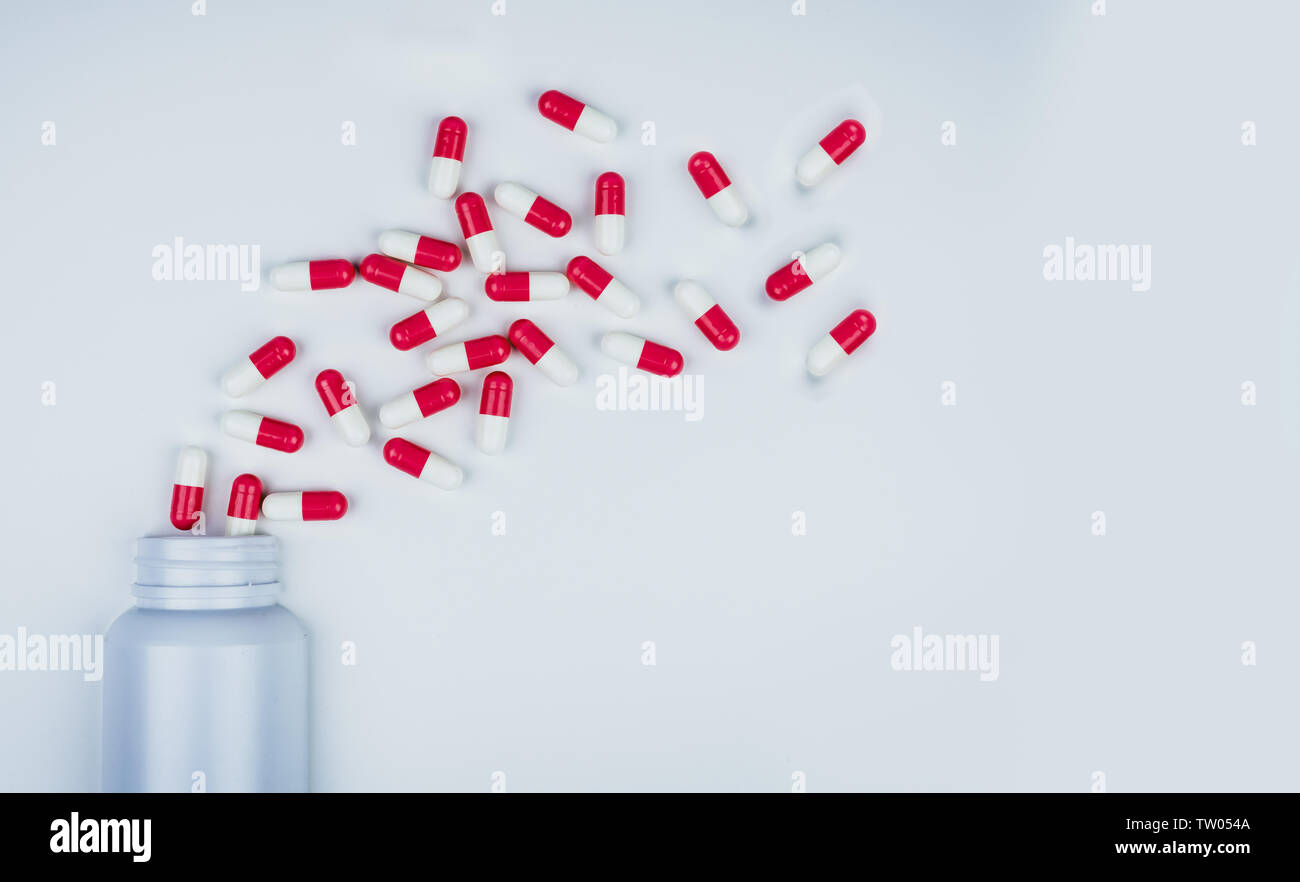 Red-white antibiotic capsule pills spread out of white plastic drug ...