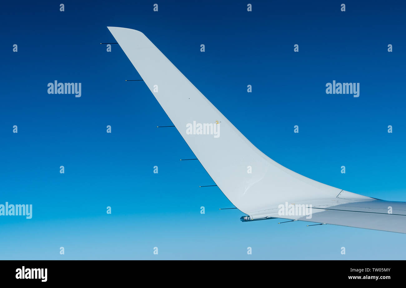 Wing of plane over white clouds. Airplane flying on clear blue sky ...