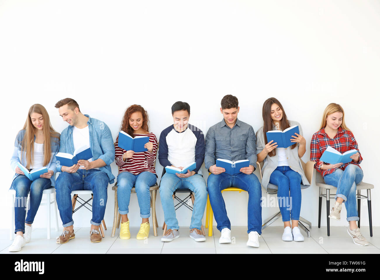 Group of people reading books while sitting near light wall Stock Photo ...