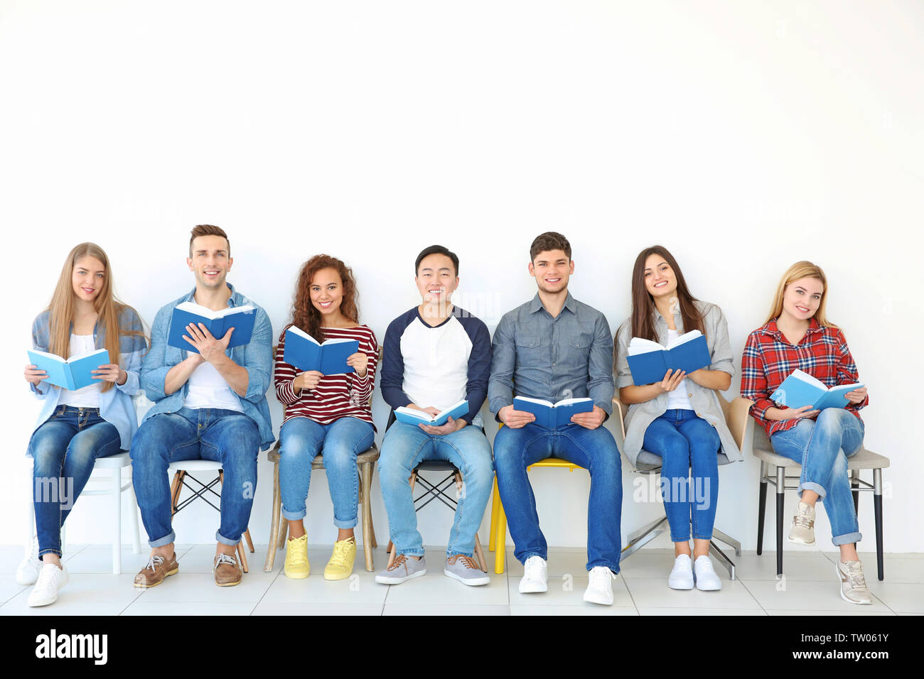 Group of people reading books while sitting near light wall Stock Photo ...