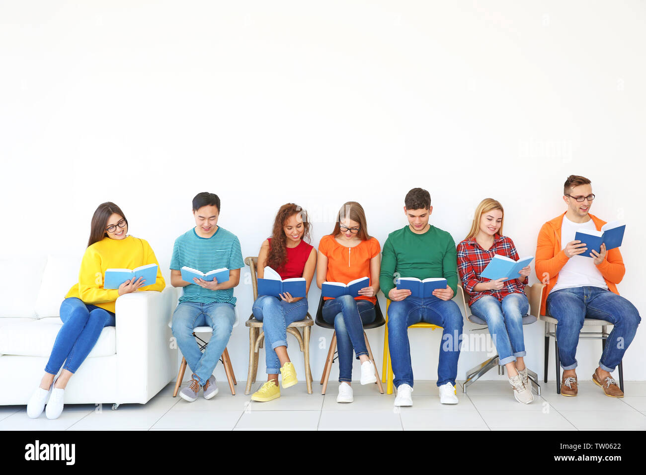 Group of people reading books while sitting near light wall Stock Photo ...