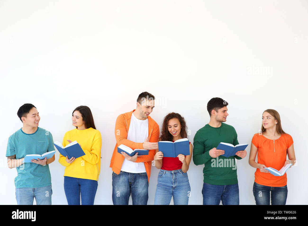 Group of people reading books while standing near light wall Stock ...