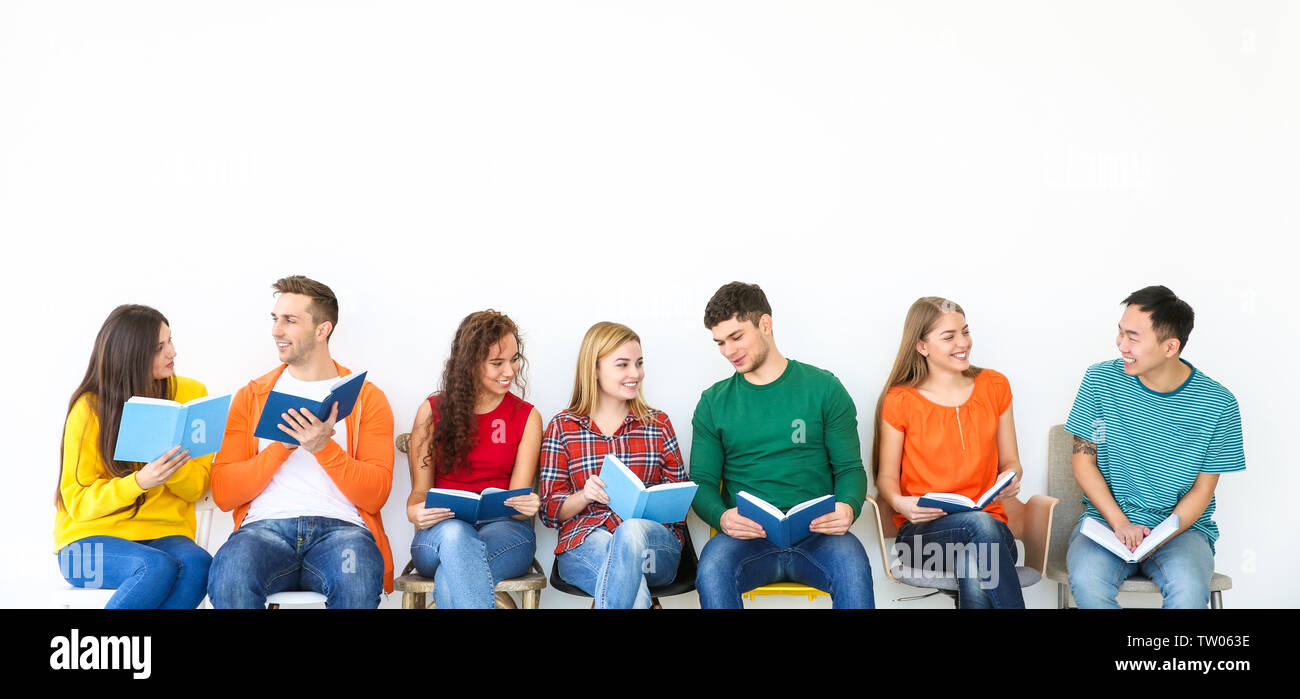 Group of people reading books while sitting near light wall Stock Photo ...