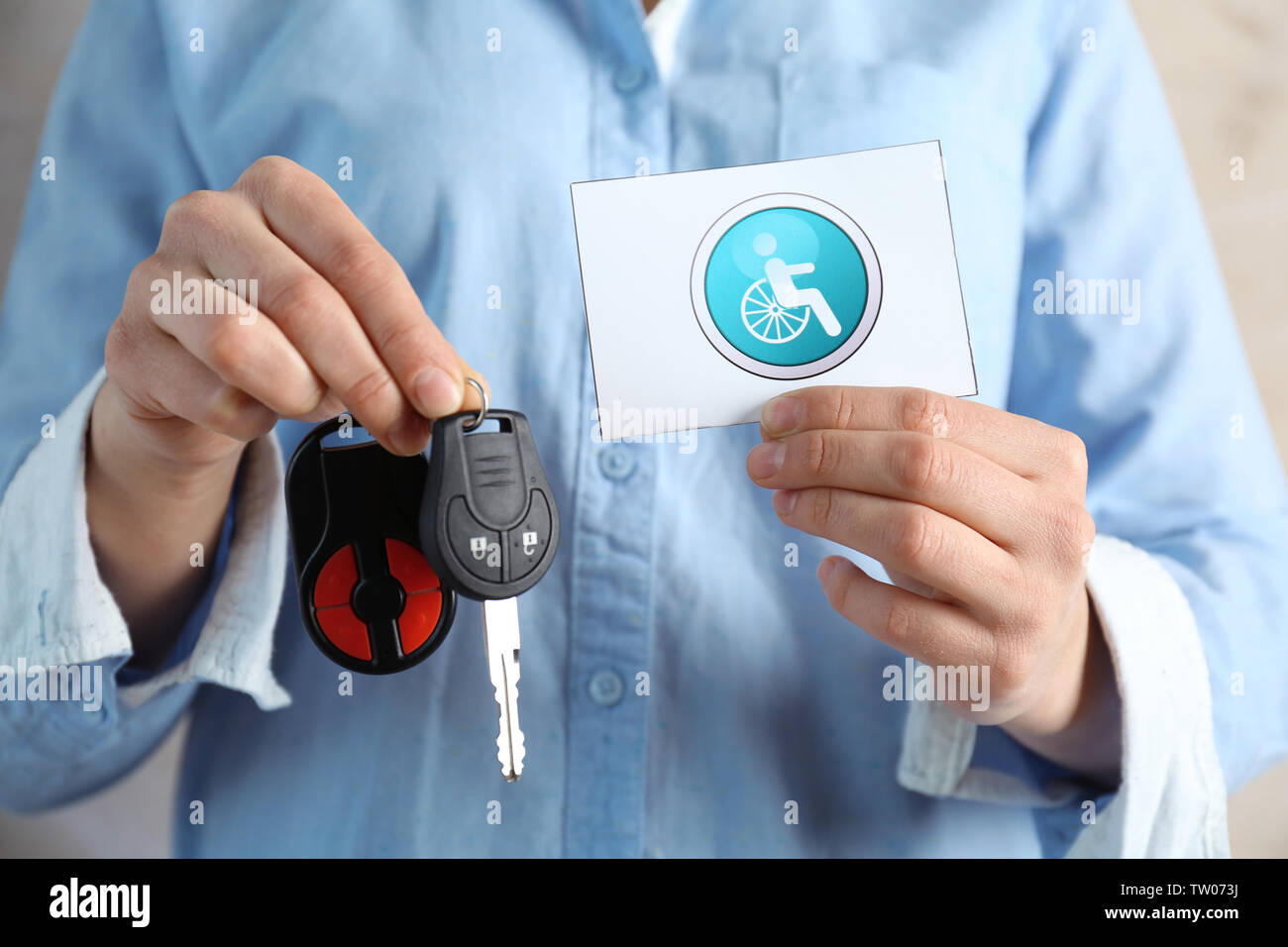 Woman holding car key and card with handicap sign, closeup Stock Photo ...