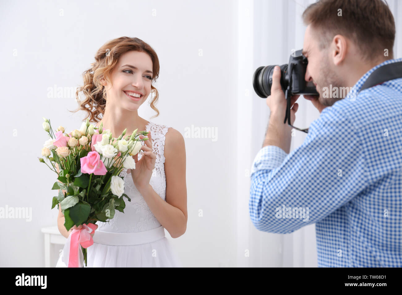 Wedding photographer taking photo of beautiful bride in studio Stock ...