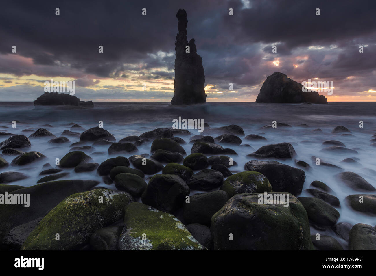 Green stones beach and giant rocks in the ocean at sunrise Stock Photo ...